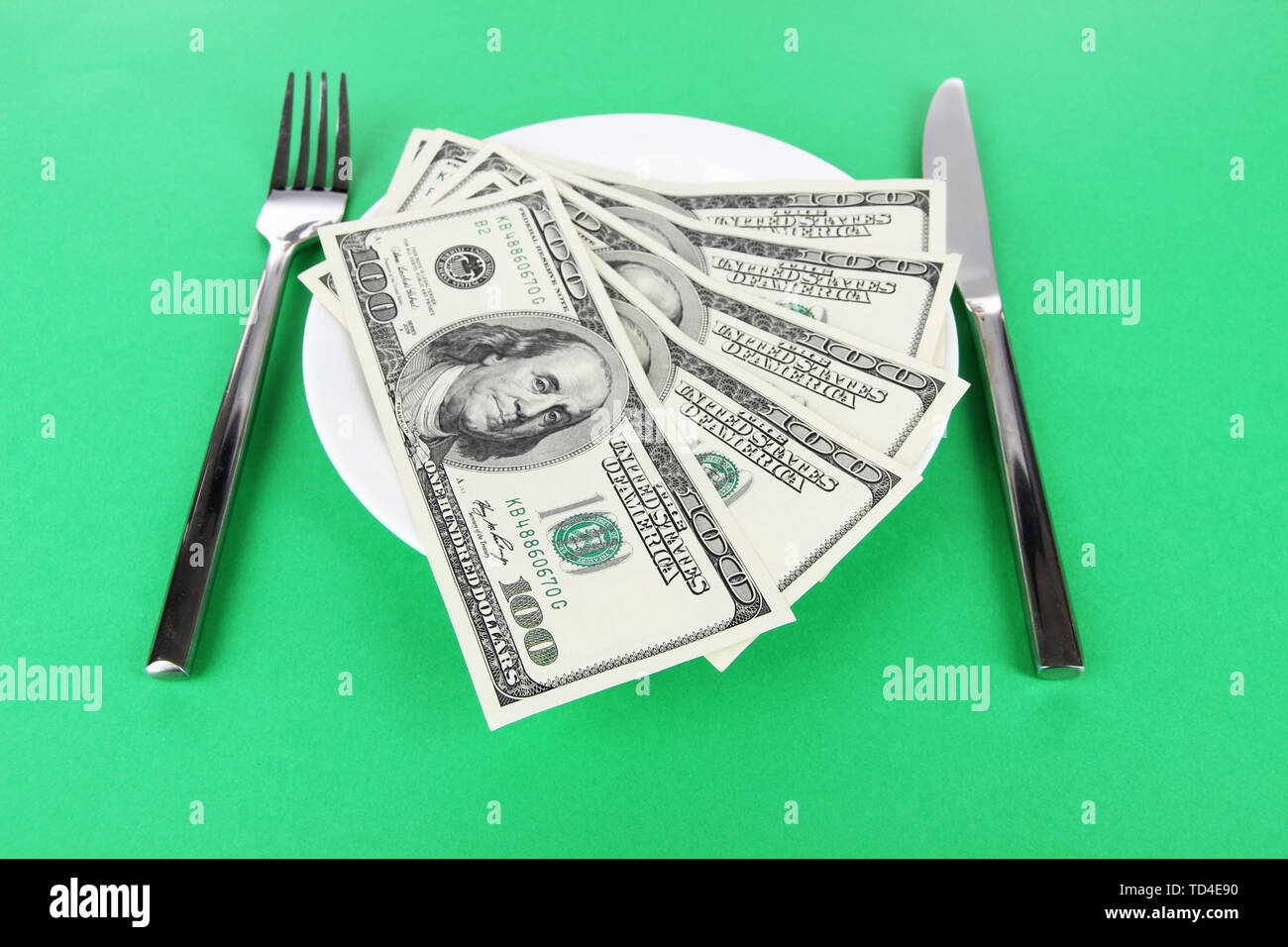 Money on plate on green background Stock Photo - Alamy