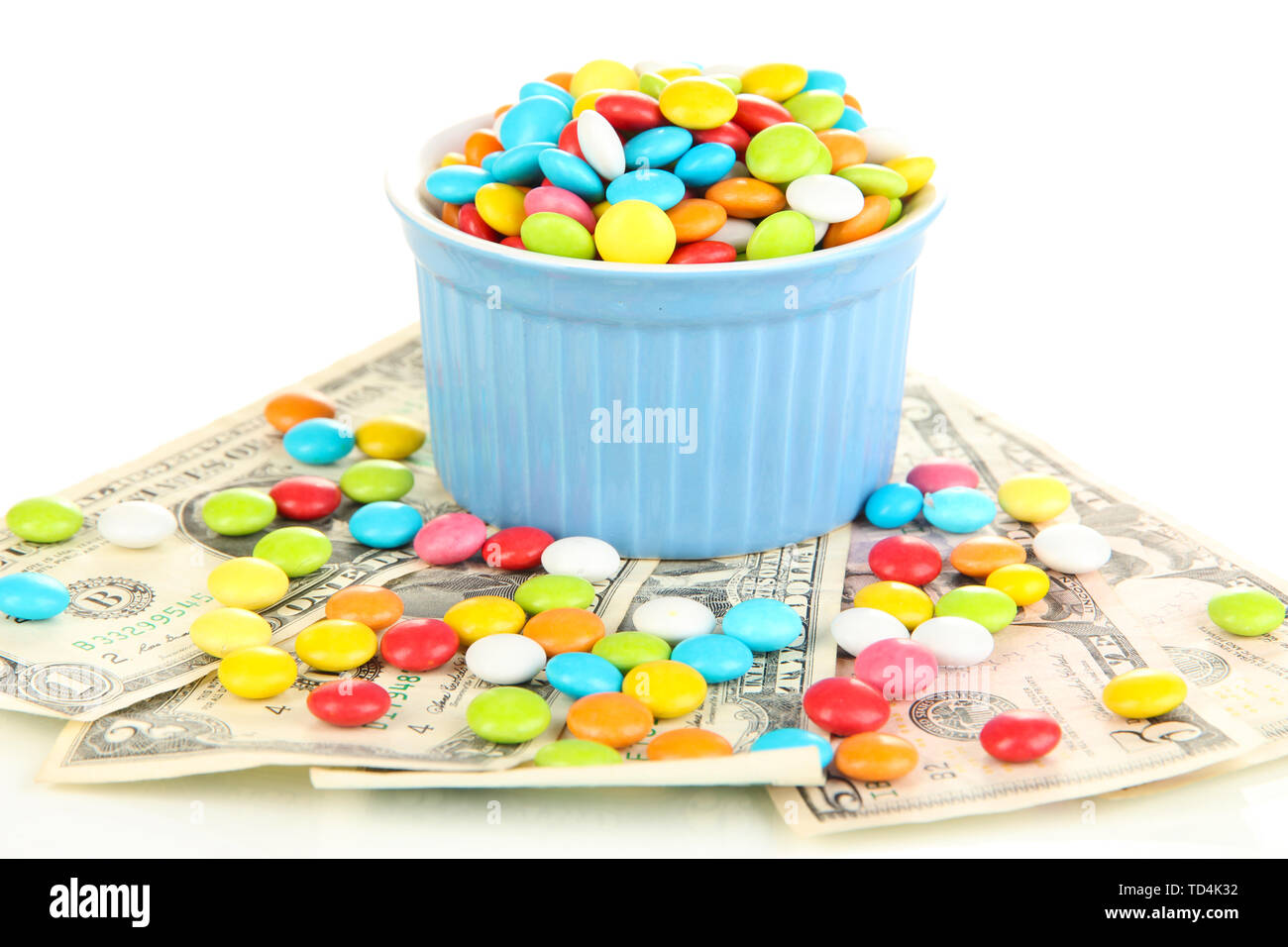 Bowl with colorful candies standing on dollar banknotes isolated on ...