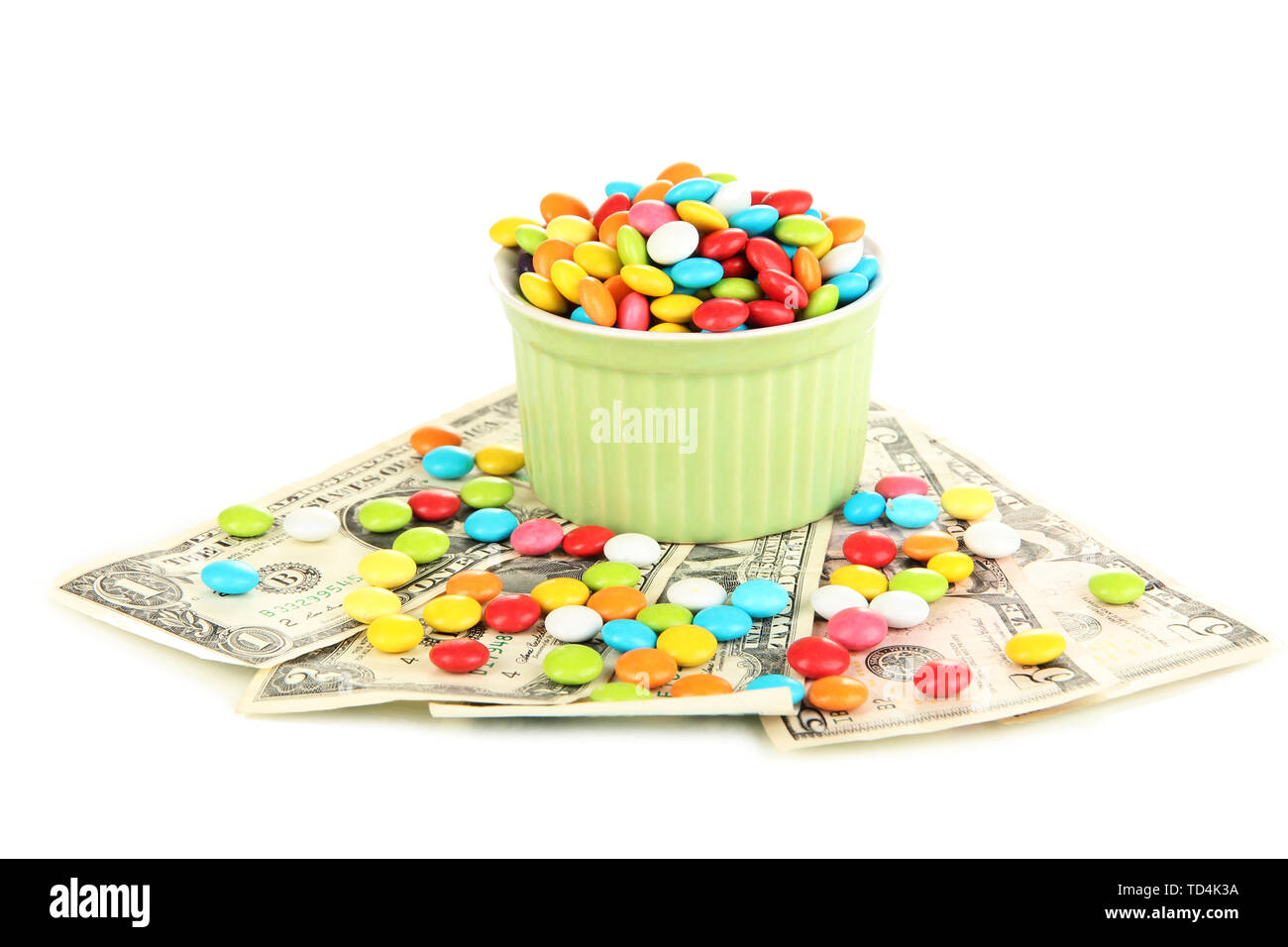 Bowl with colorful candies standing on dollar banknotes isolated on ...