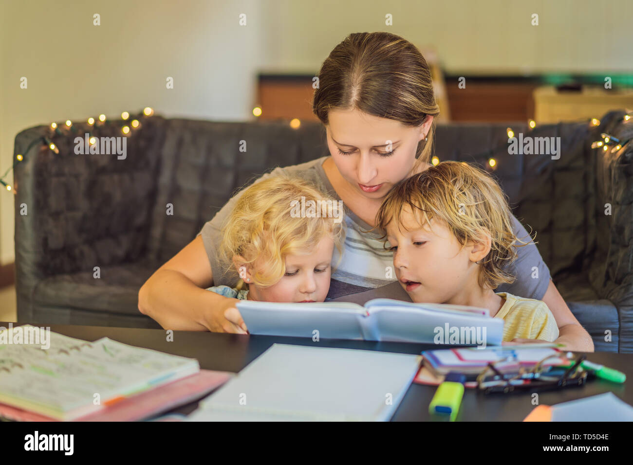 Teacher, tutor for home schooling Boy and girl at the table. Or mother, daughter and son ...
