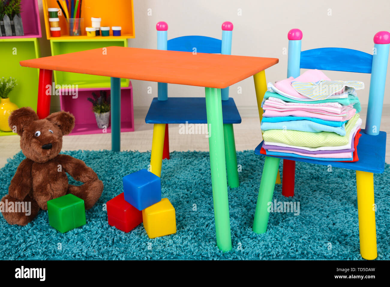 Small and colorful table and chairs with baby clothes Stock Photo - Alamy