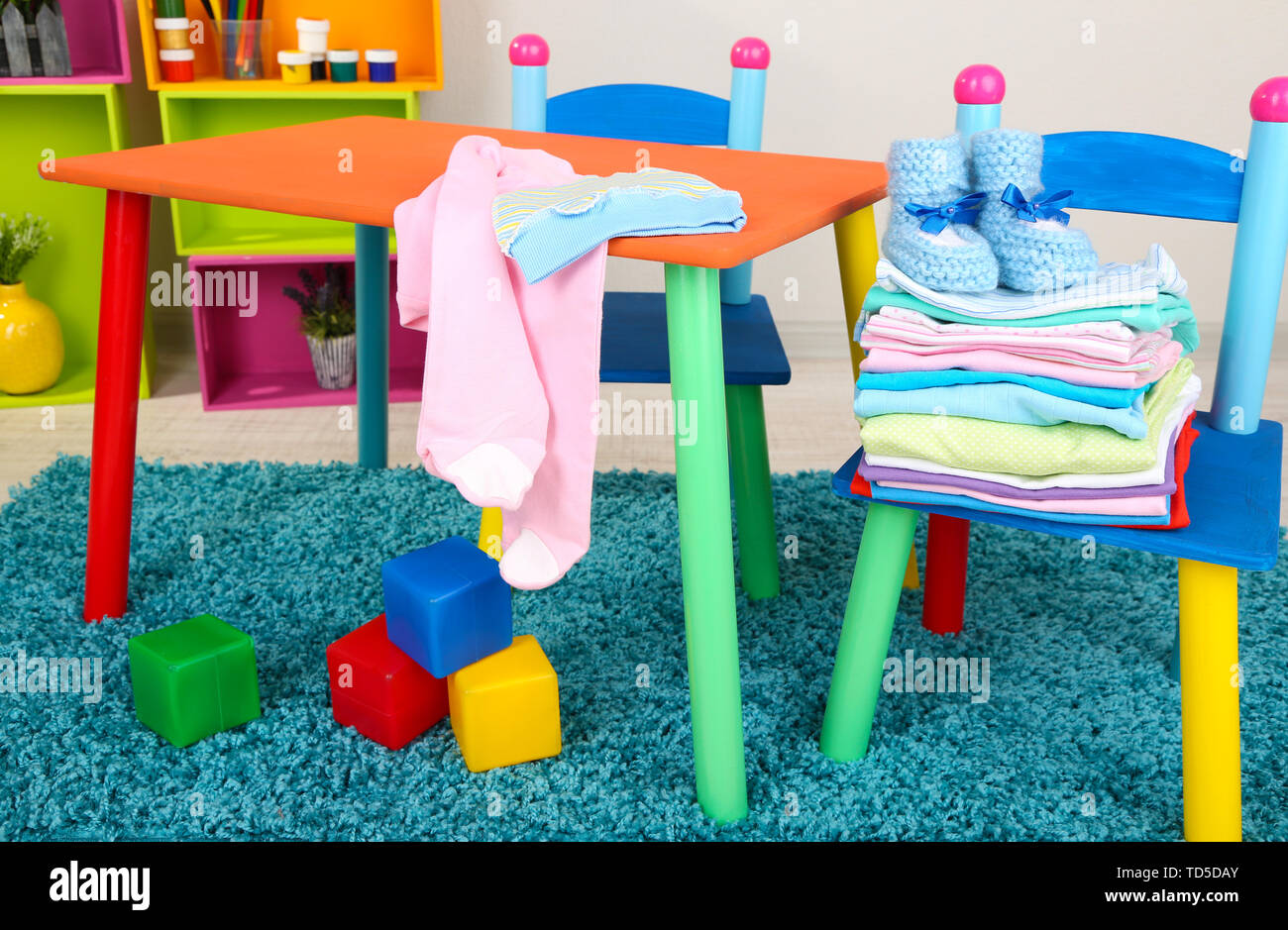 Small and colorful table and chairs with baby clothes Stock Photo - Alamy
