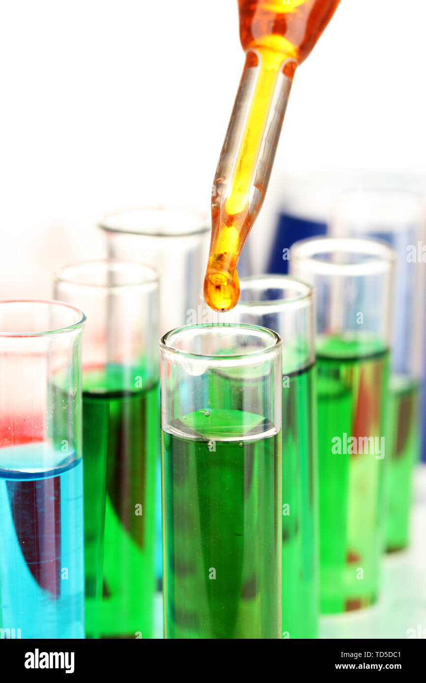 Laboratory pipette with drop of color liquid over glass test tubes ...