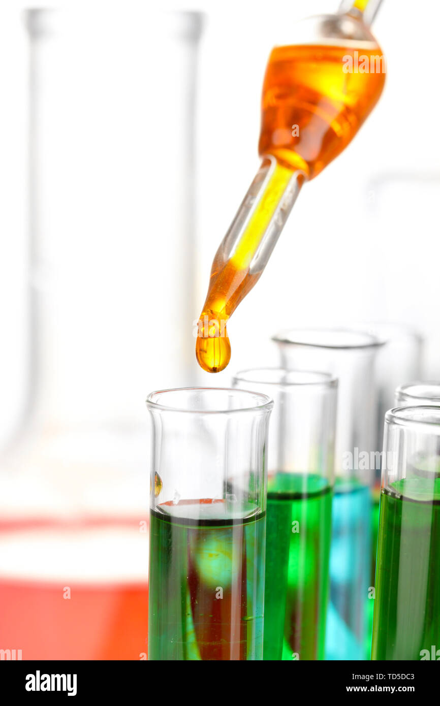 Laboratory pipette with drop of color liquid over glass test tubes ...