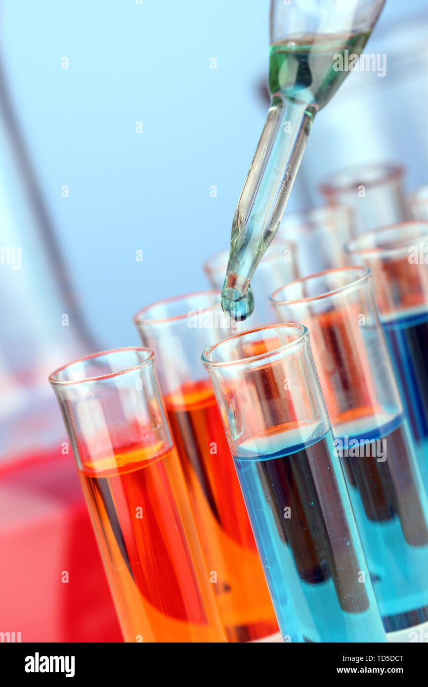 Laboratory pipette with drop of color liquid over glass test tubes ...