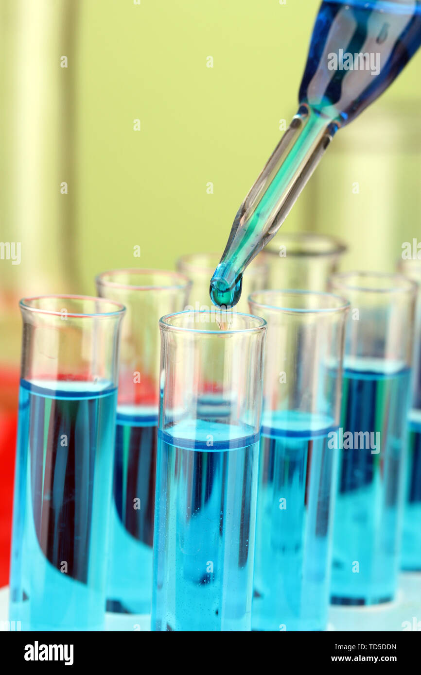 Laboratory pipette with drop of color liquid over glass test tubes ...