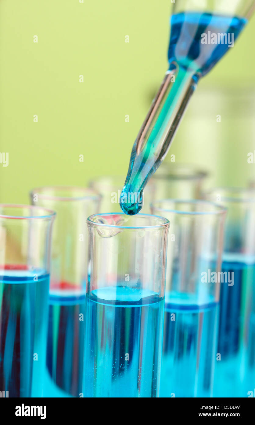Laboratory pipette with drop of color liquid over glass test tubes ...