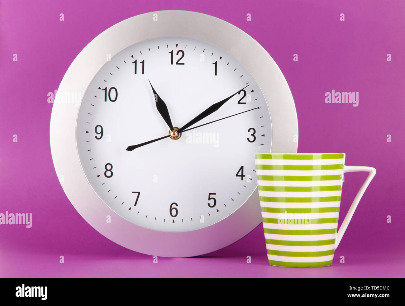 Cup tea and clock on purple background Stock Photo - Alamy