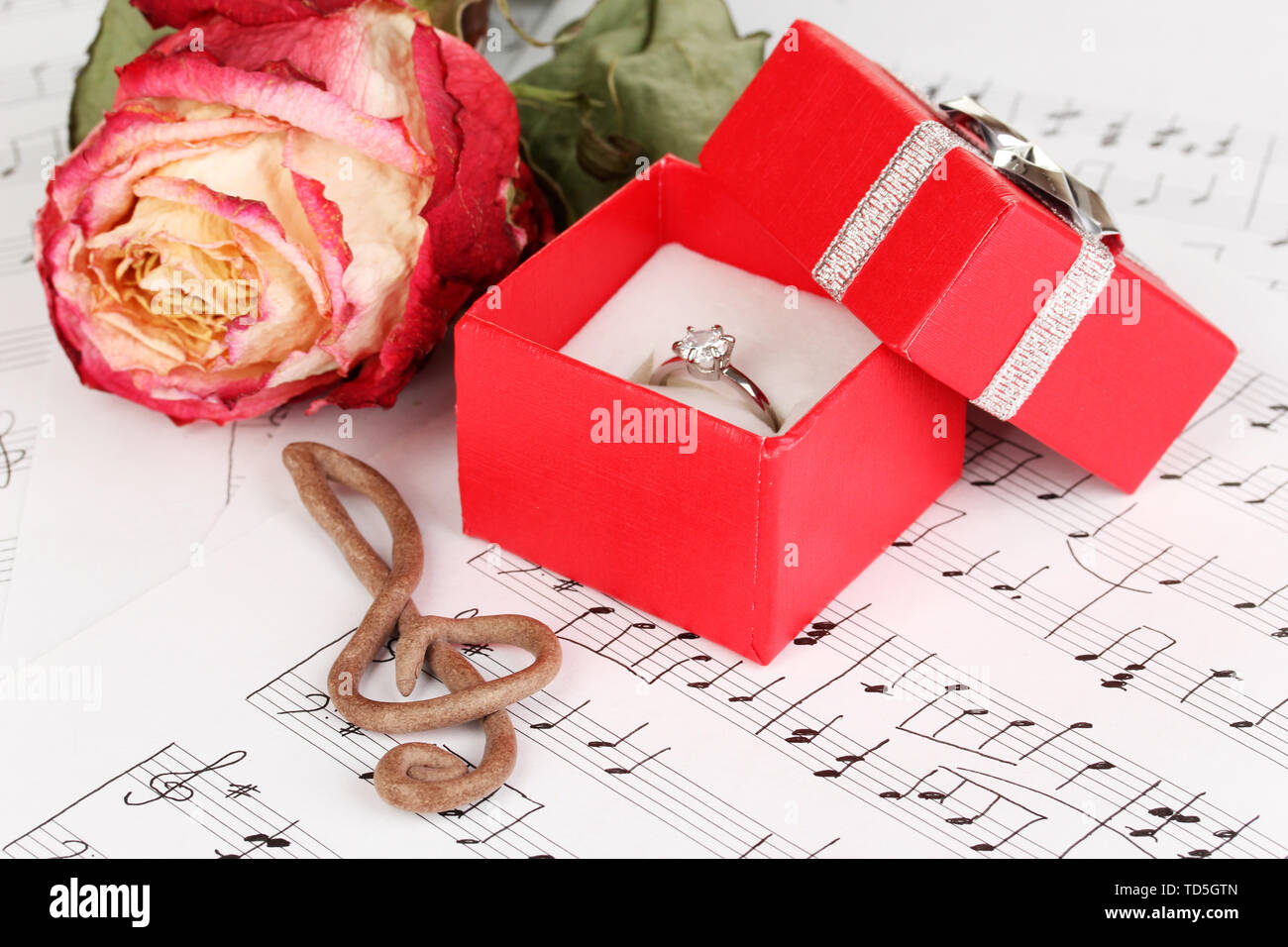 Treble clef, rose and box holding wedding ring on musical background ...