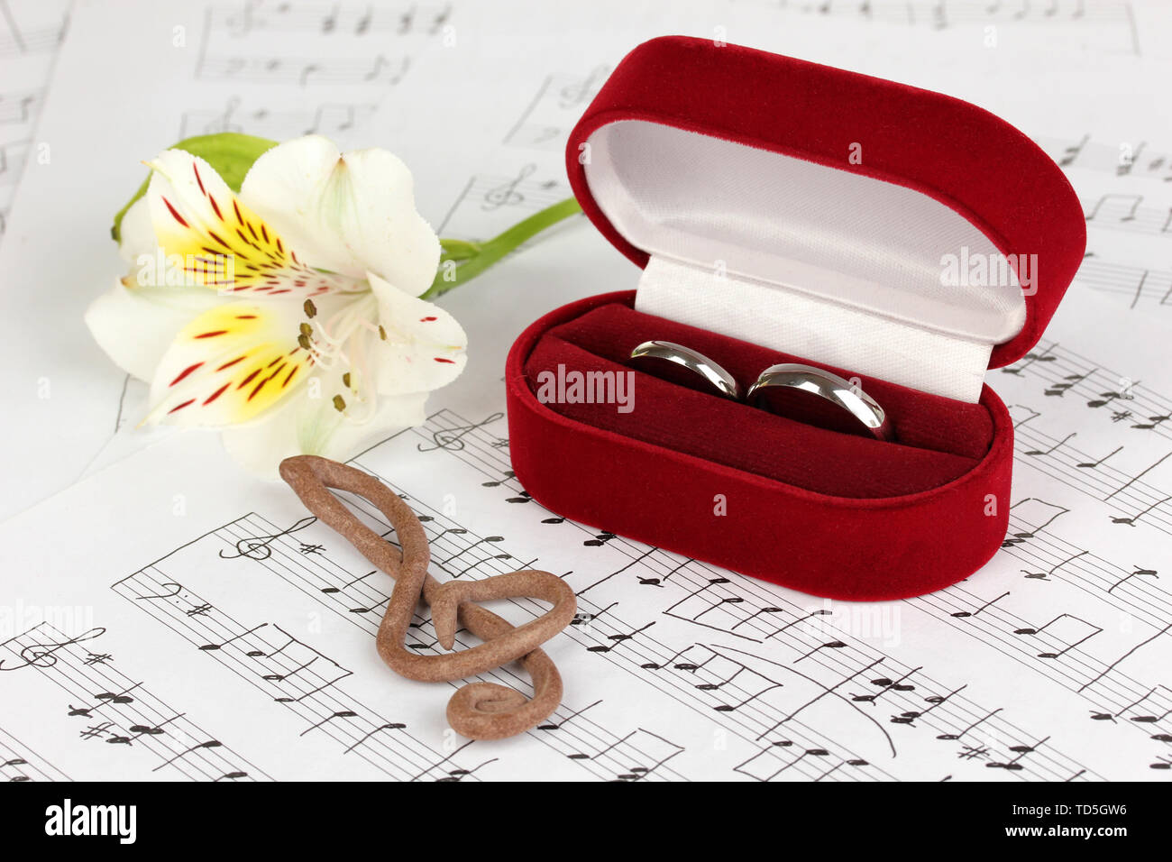 Treble clef, flower and box holding wedding rings on musical background ...
