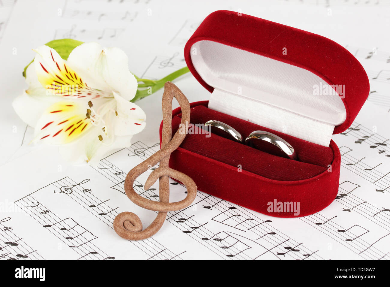Treble clef, flower and box holding wedding rings on musical background ...