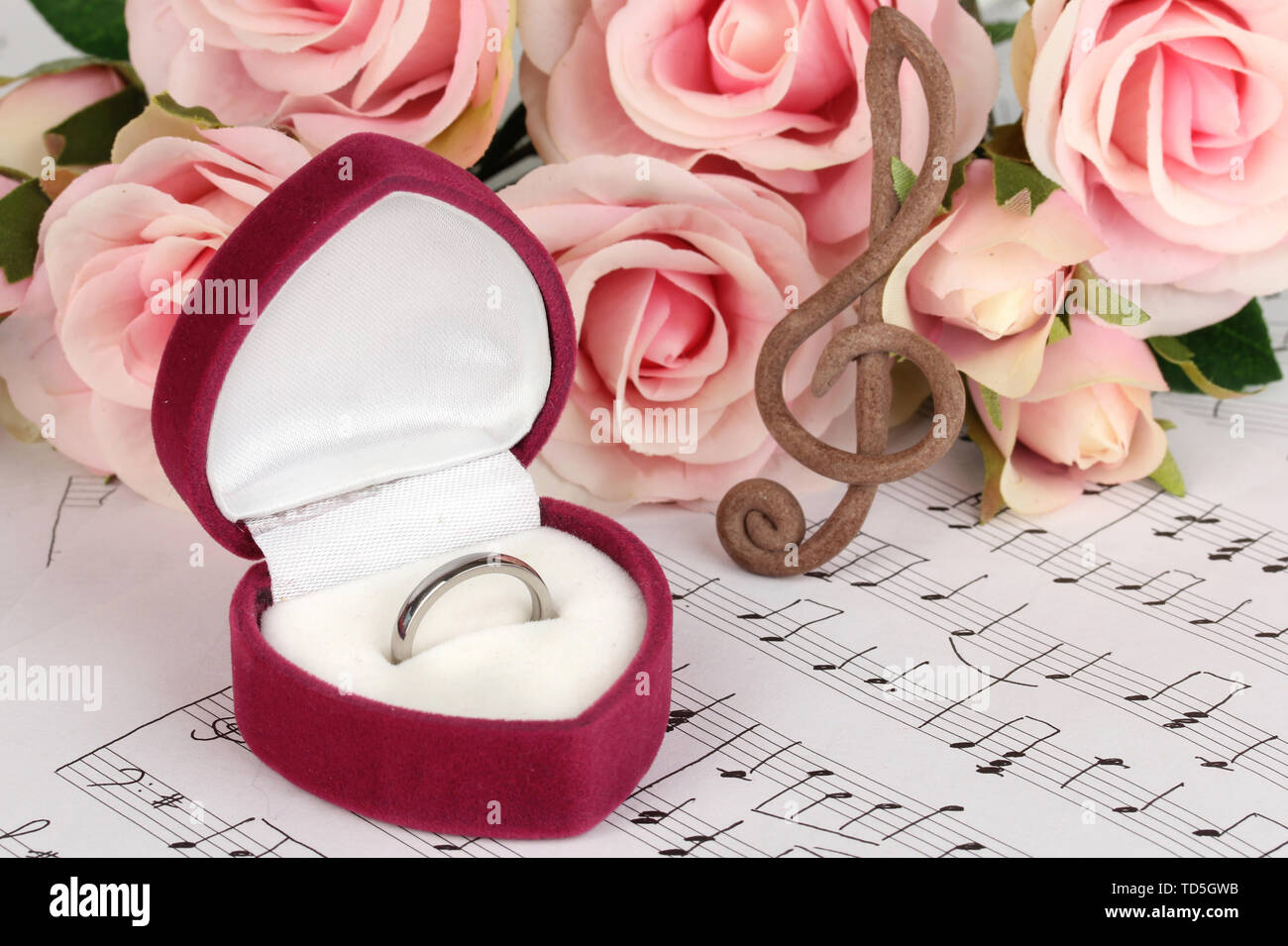 Treble clef, roses and box holding wedding ring on musical background ...