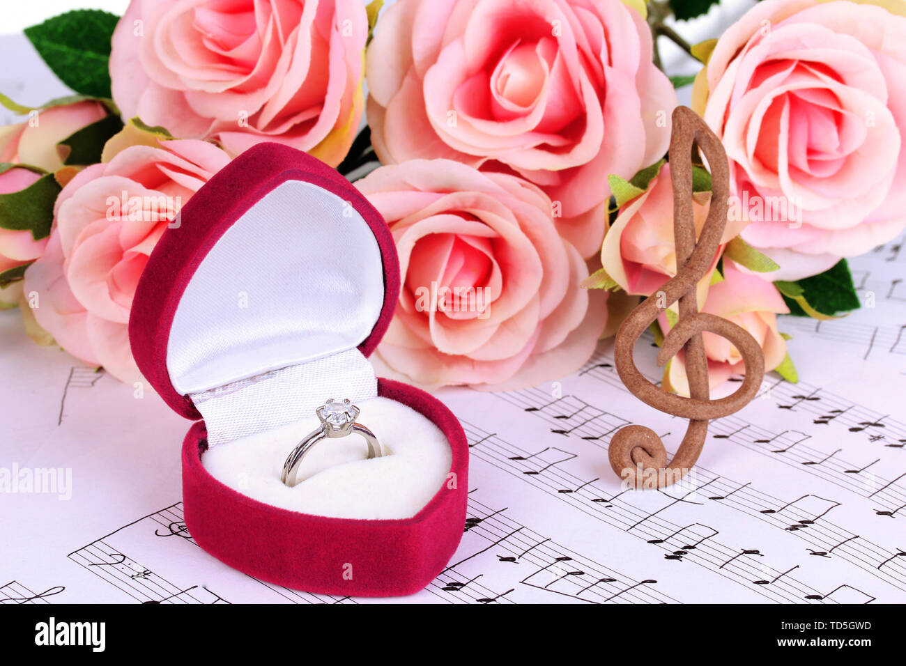 Treble clef, roses and box holding wedding ring on musical background ...