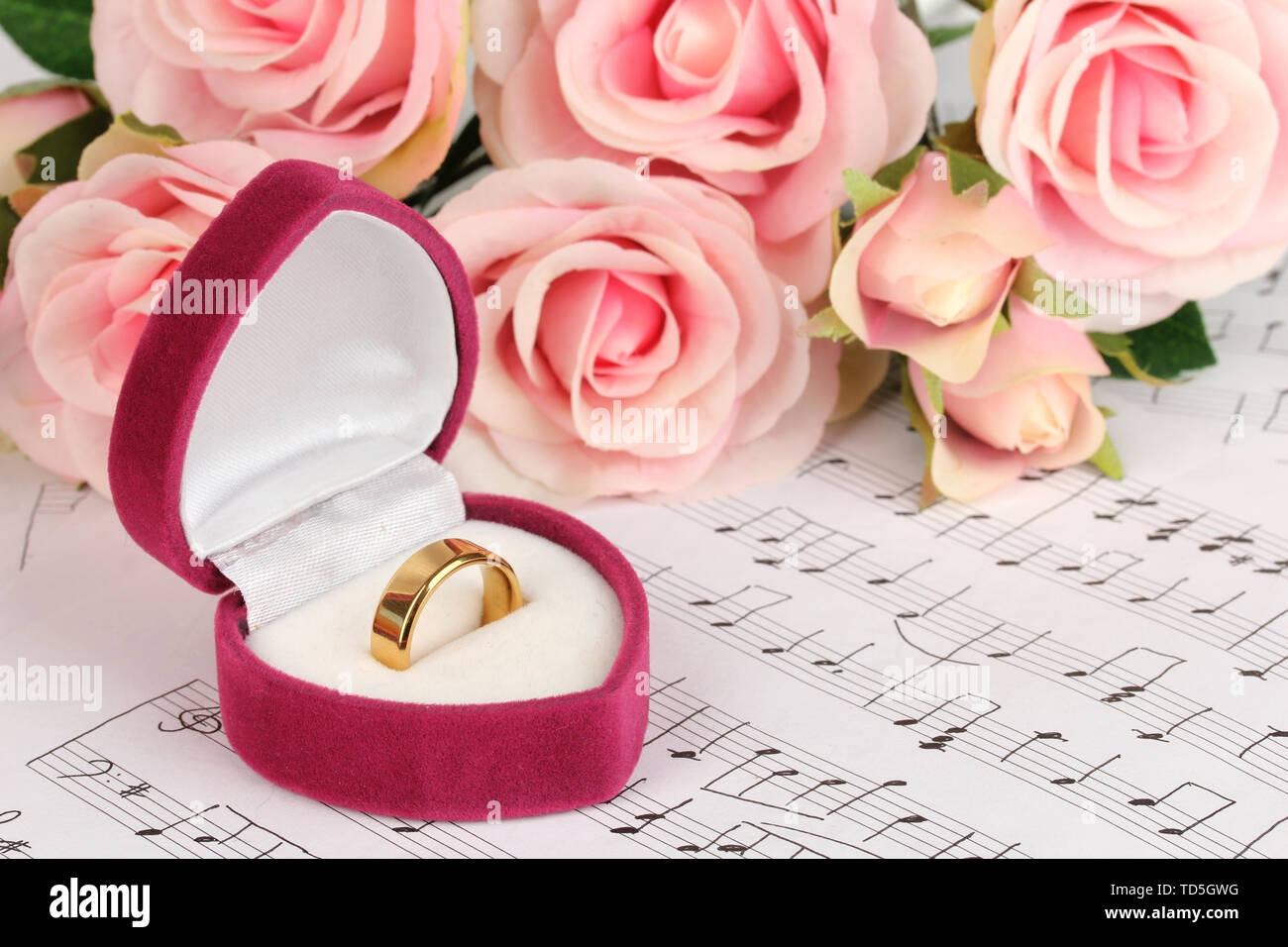Treble clef, roses and box holding wedding ring on musical background ...