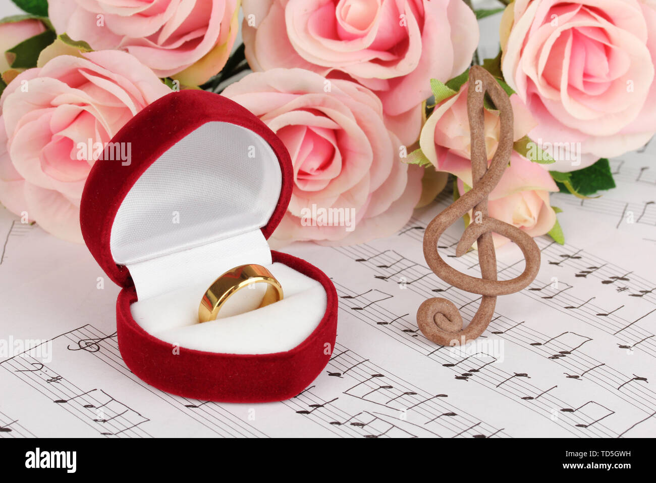 Treble clef, roses and box holding wedding ring on musical background ...