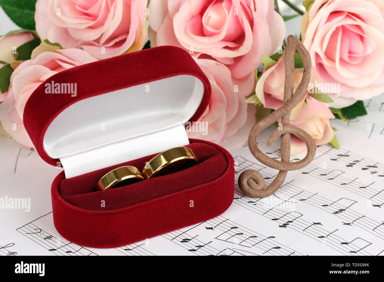 Treble clef, roses and box holding wedding rings on musical background ...