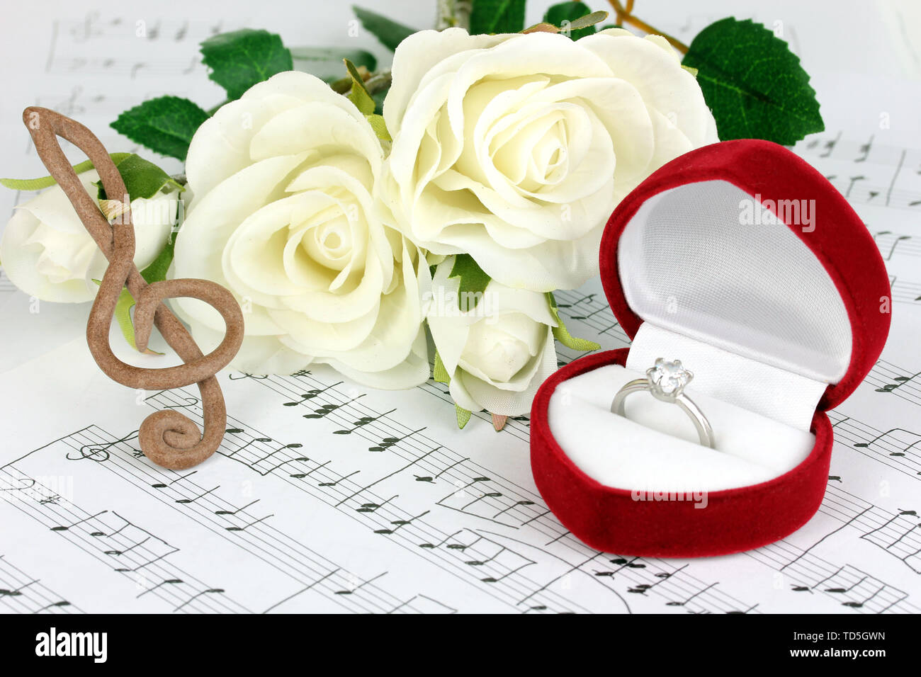 Treble clef, roses and box holding wedding ring on musical background ...