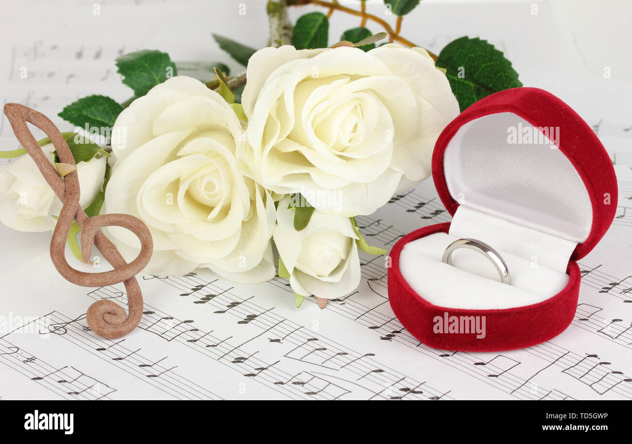 Treble clef, roses and box holding wedding ring on musical background ...