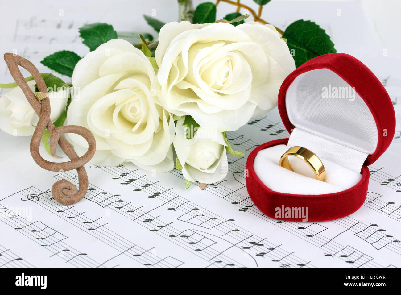 Treble clef, roses and box holding wedding ring on musical background ...