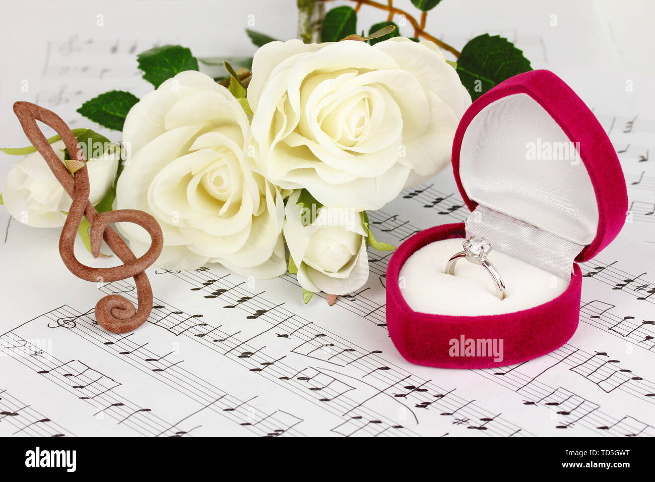 Treble clef, roses and box holding wedding ring on musical background ...