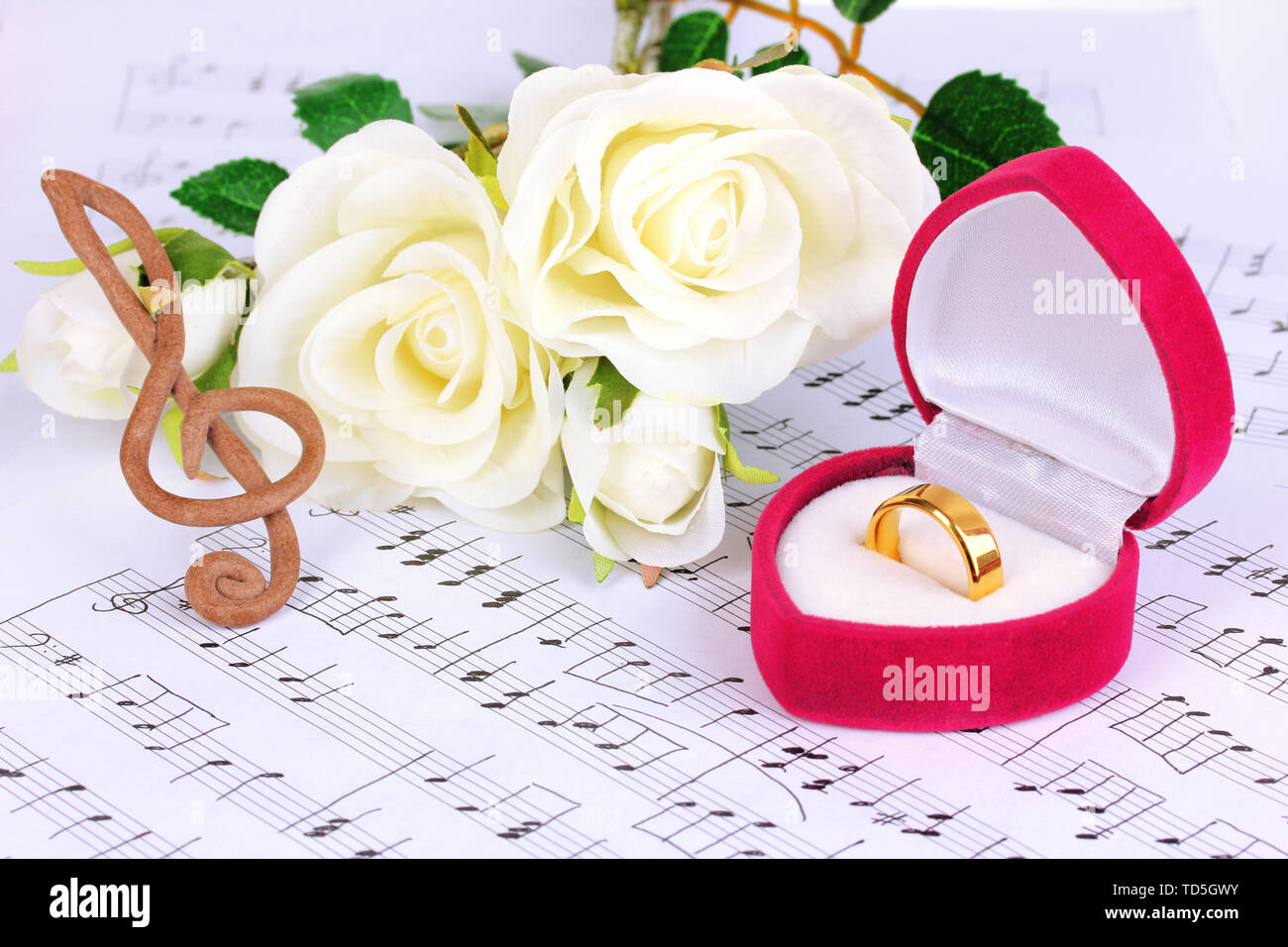 Treble clef, roses and box holding wedding ring on musical background ...