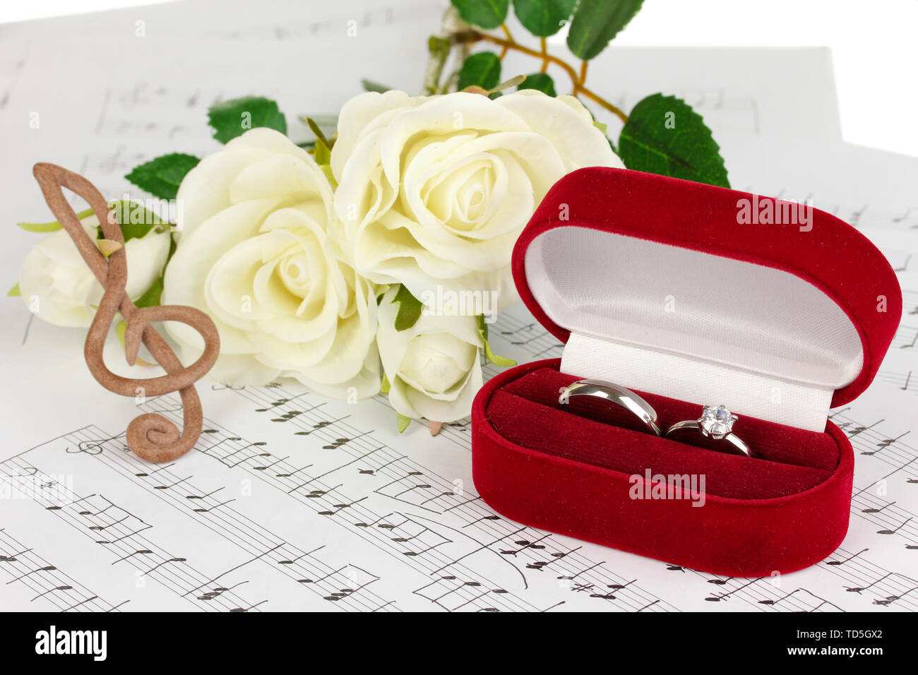 Treble clef, roses and box holding wedding rings on musical background ...