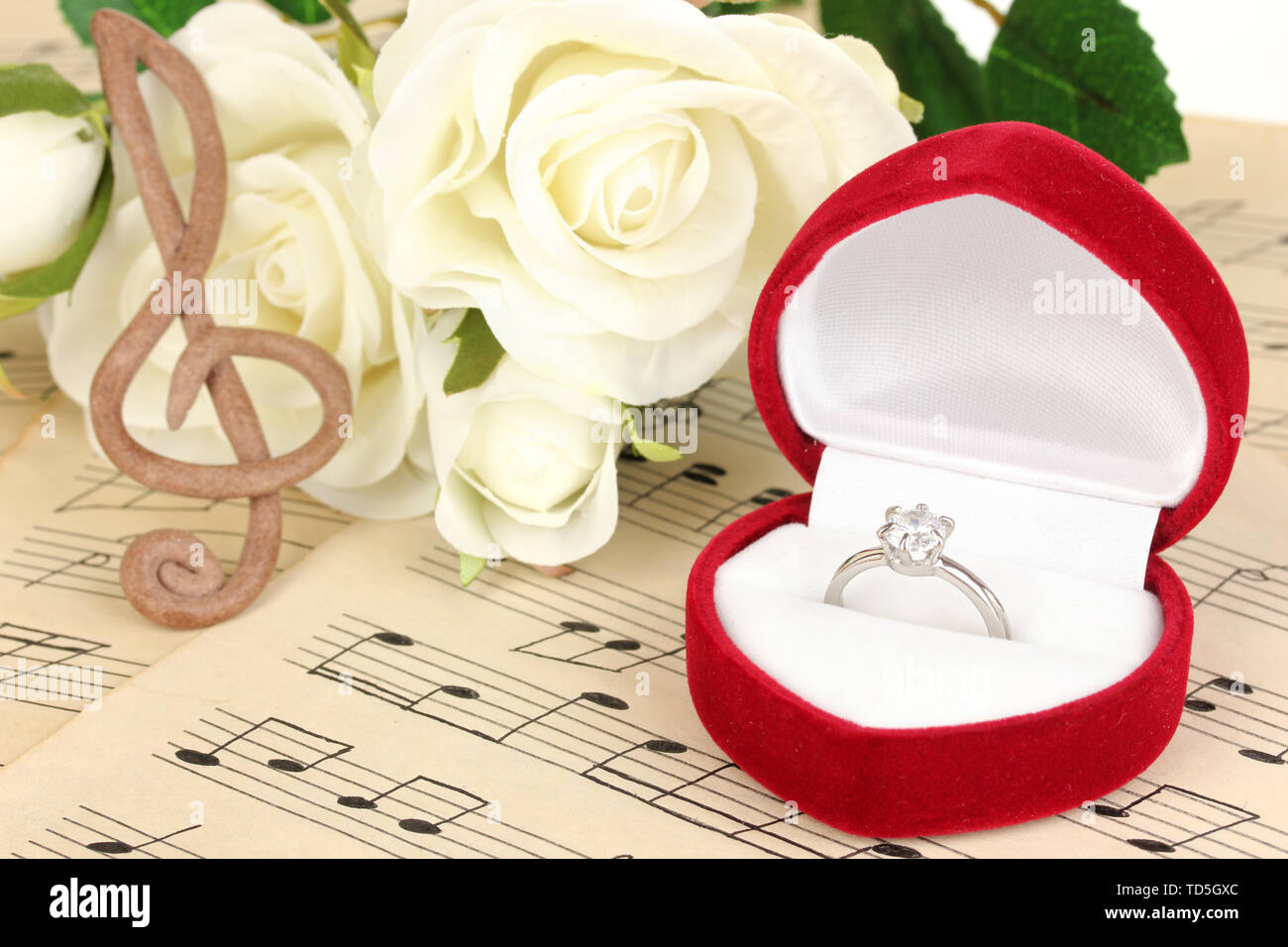 Treble clef, roses and box holding wedding ring on musical background ...