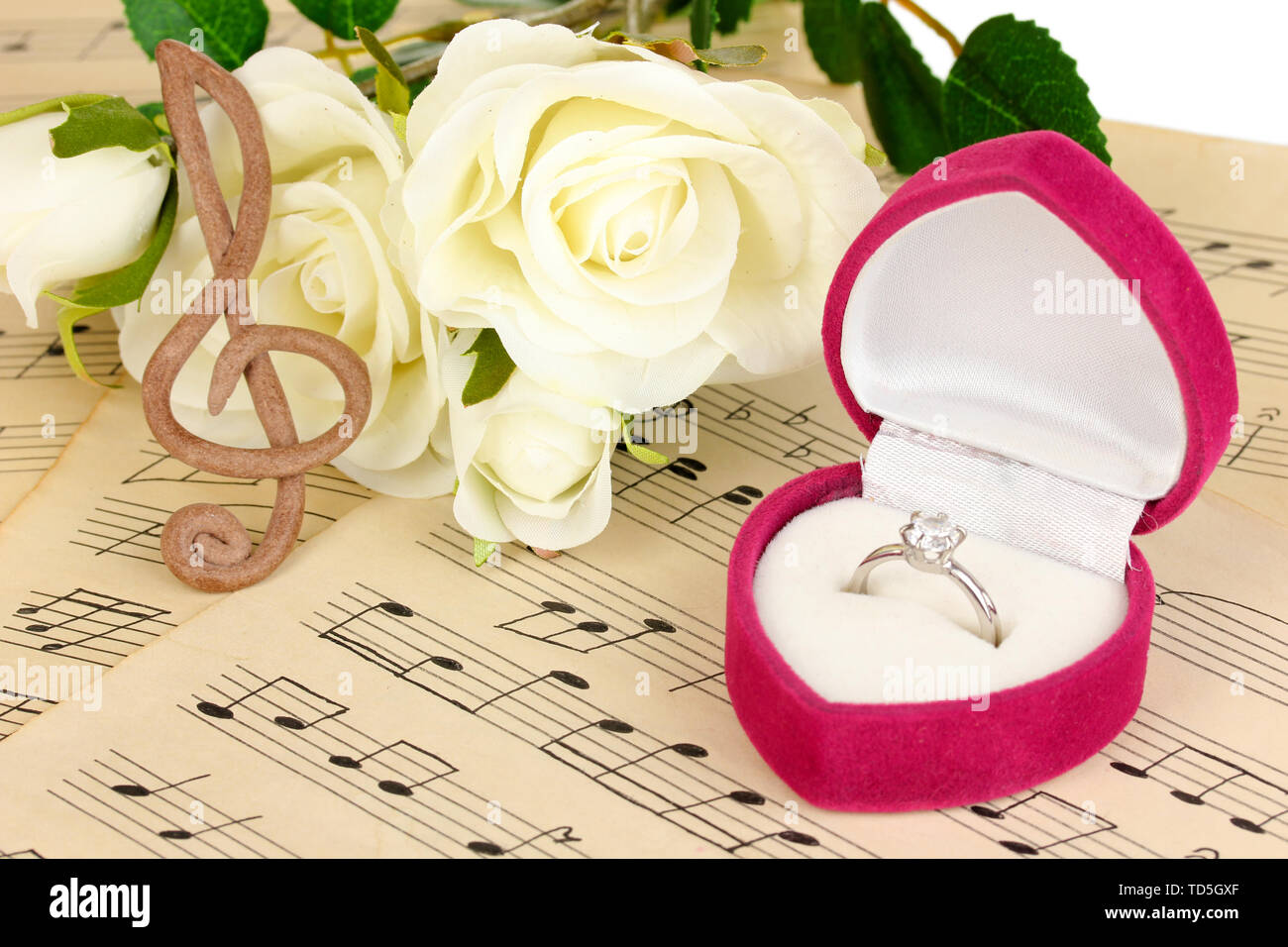 Treble clef, roses and box holding wedding ring on musical background ...