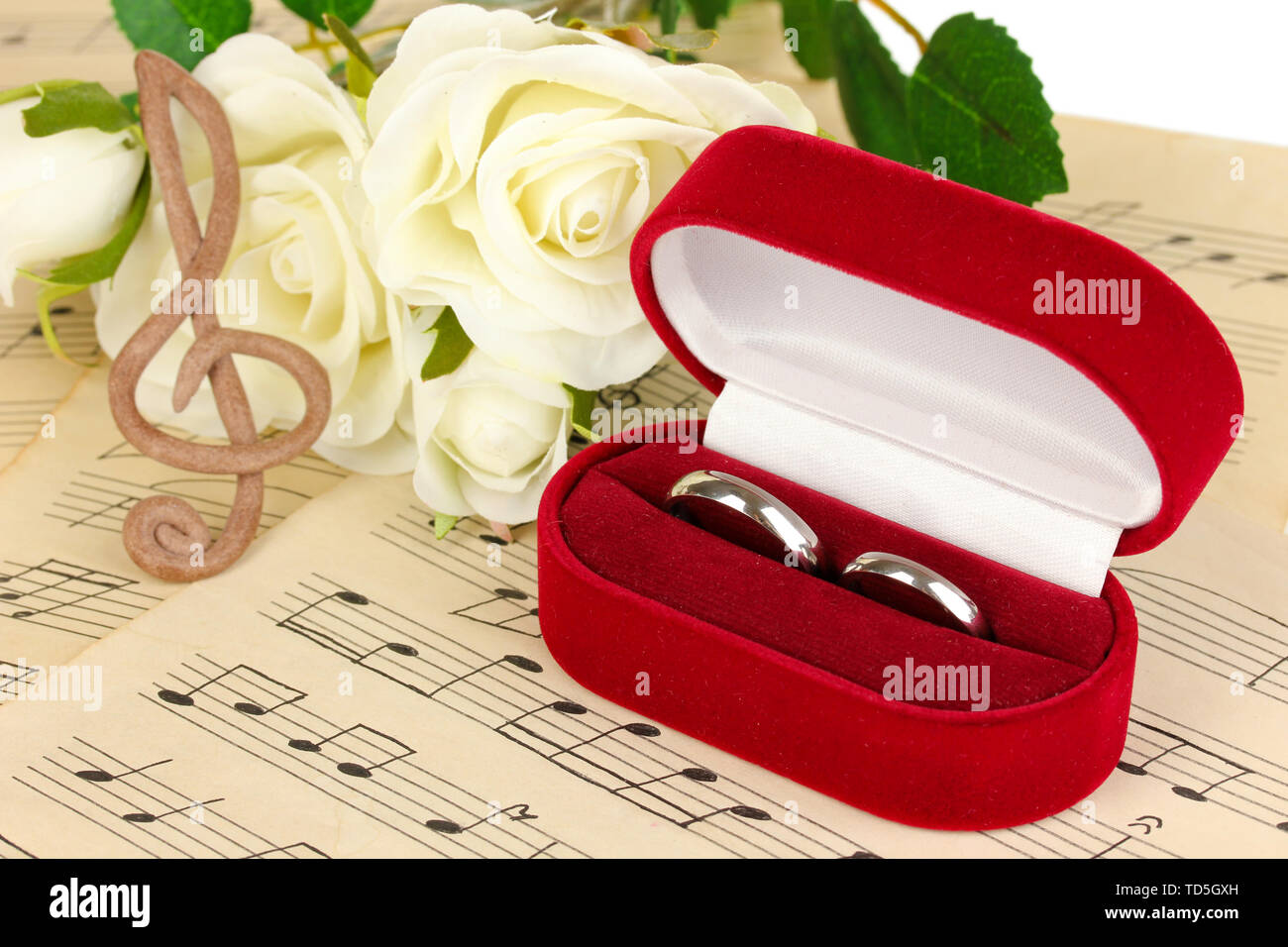 Treble clef, roses and box holding wedding rings on musical background ...