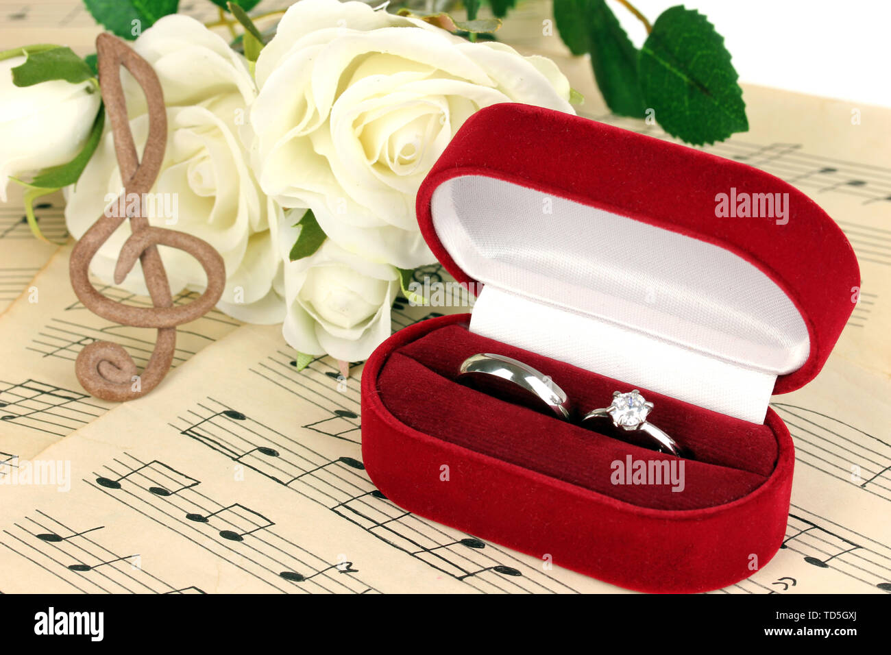 Treble clef, roses and box holding wedding rings on musical background ...