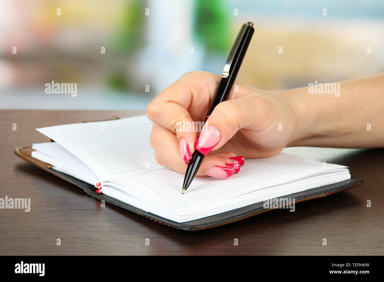 Hand signing in notebook, on bright background Stock Photo - Alamy