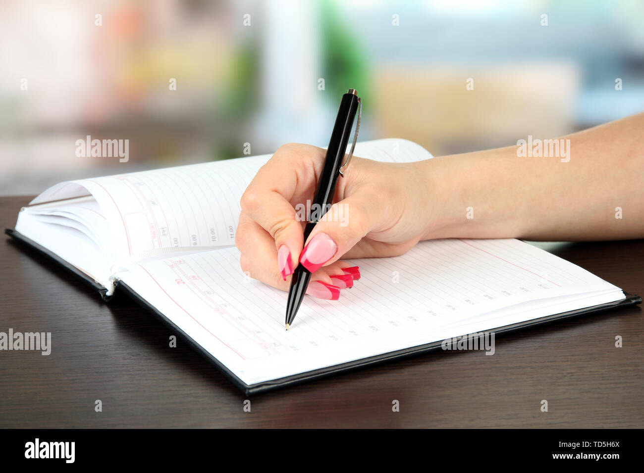 Hand signing in notebook, on bright background Stock Photo - Alamy