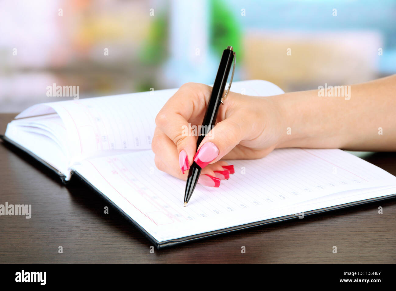 Hand signing in notebook, on bright background Stock Photo - Alamy