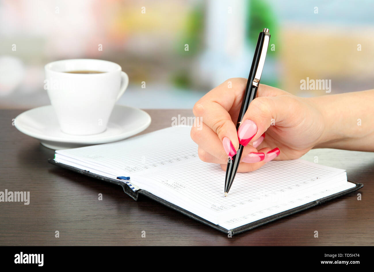 Hand signing in notebook, on bright background Stock Photo - Alamy
