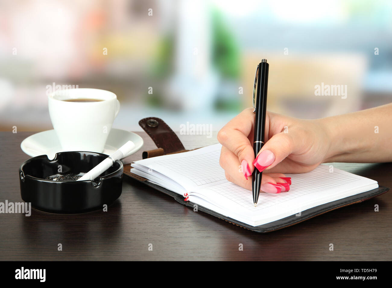 Hand signing in notebook, on bright background Stock Photo - Alamy