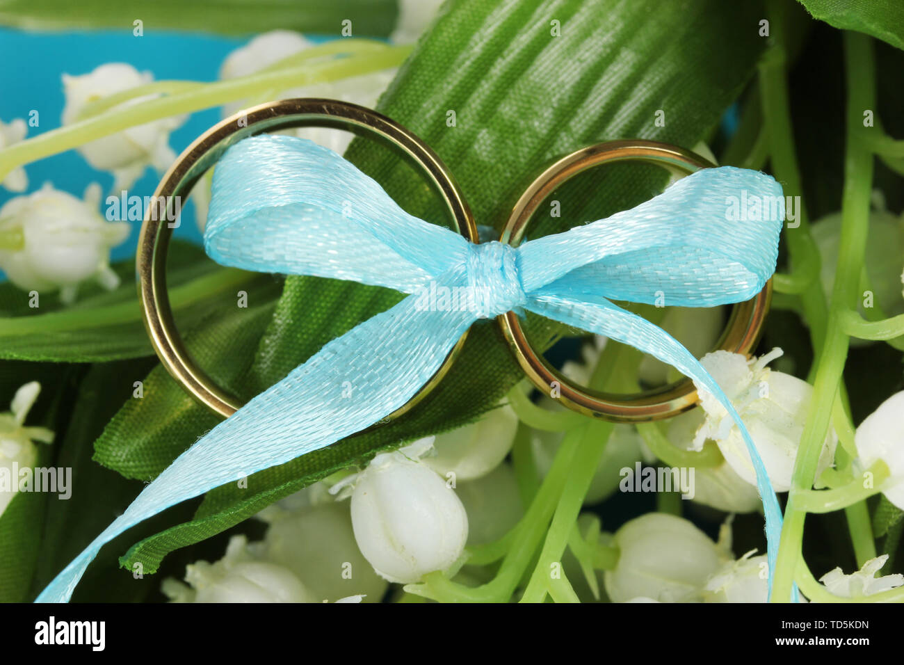 Wedding rings tied with ribbon on flower background Stock Photo - Alamy