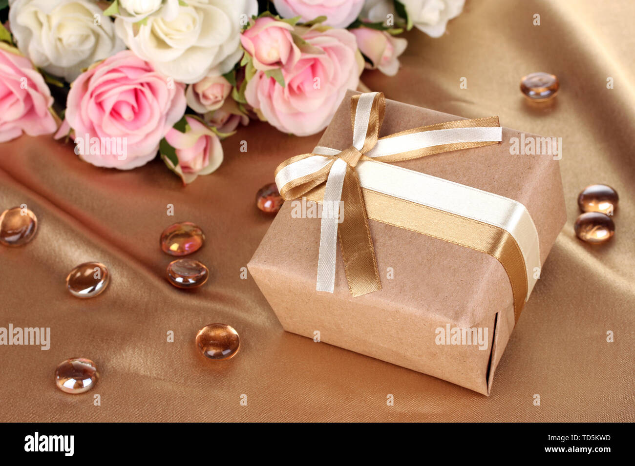 Beautiful gift on flowers background Stock Photo - Alamy