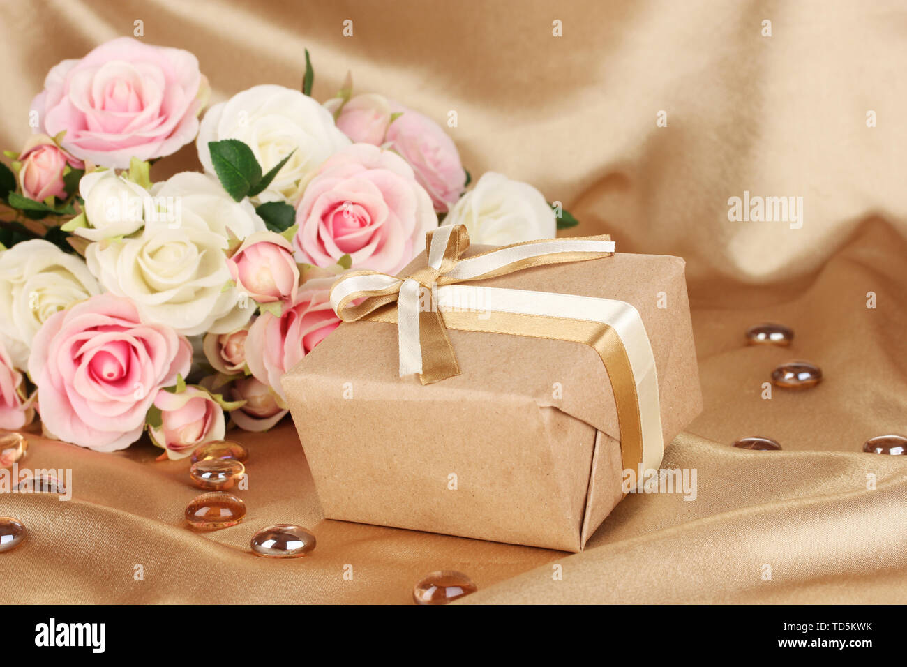 Beautiful gift on flowers background Stock Photo - Alamy