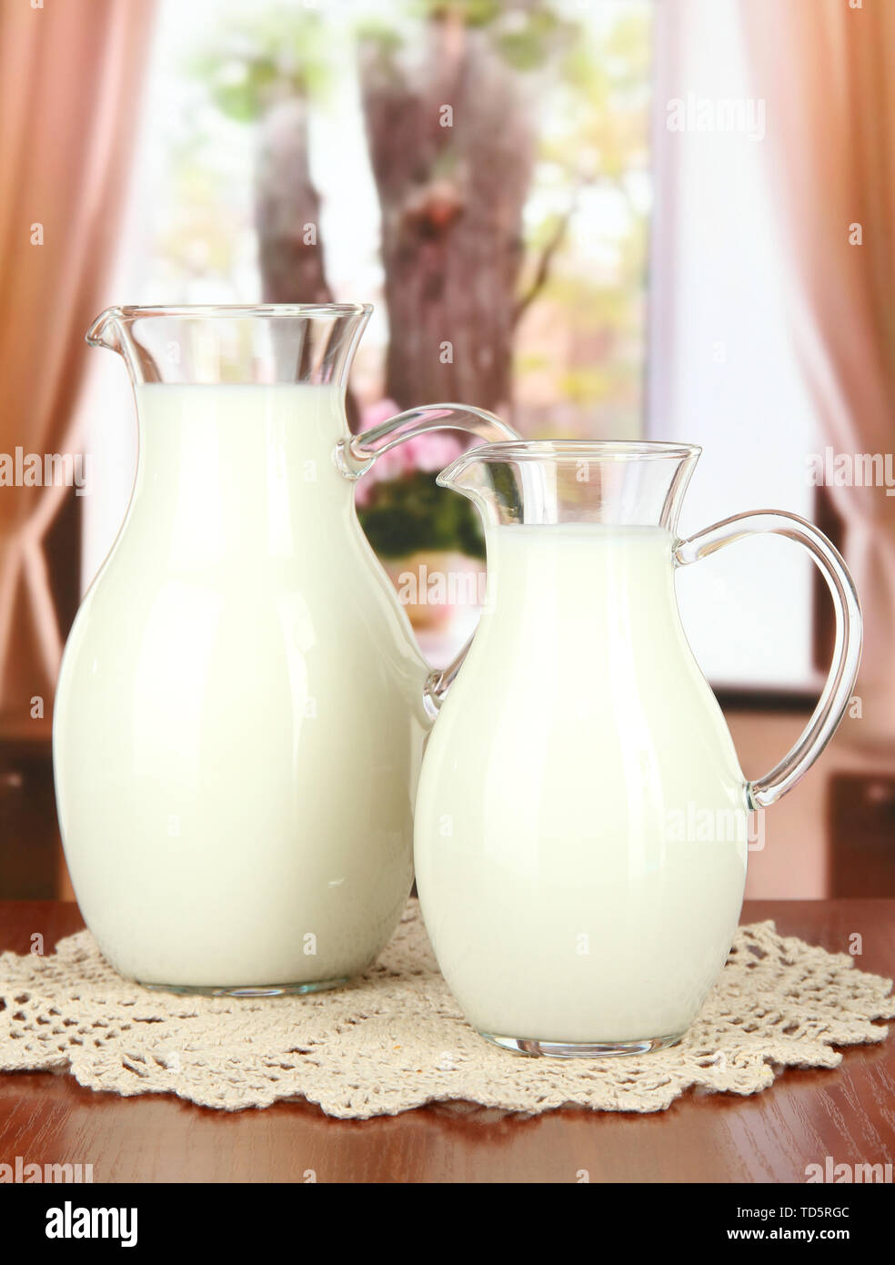 Pitchers of milk on table in room Stock Photo - Alamy