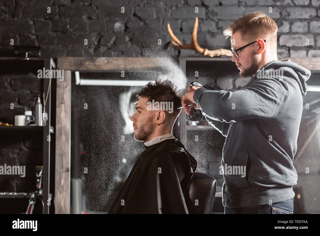Barber sprays clean water on head in barbershop. Professional trimmer ...