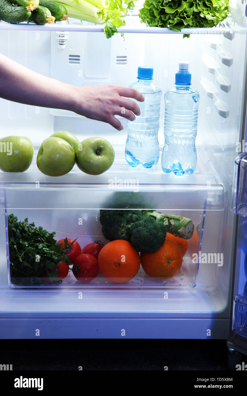 Woman's hand reaching out for food from the refrigerator, close up ...