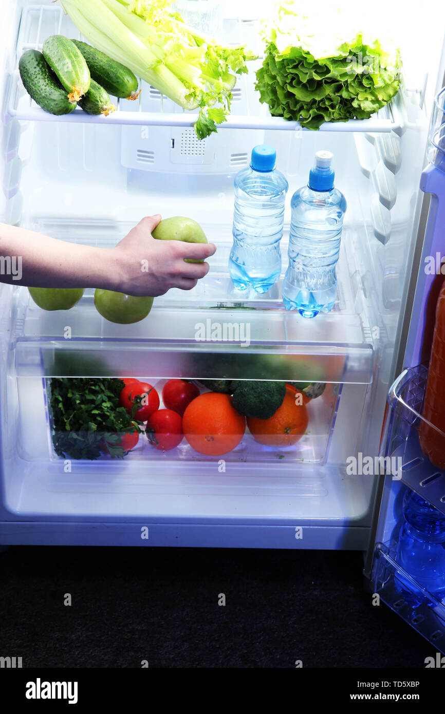 Woman's hand reaching out for food from the refrigerator, close up ...