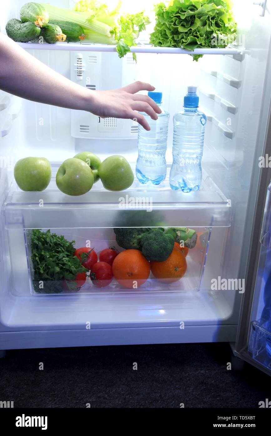Woman's hand reaching out for food from the refrigerator, close up ...