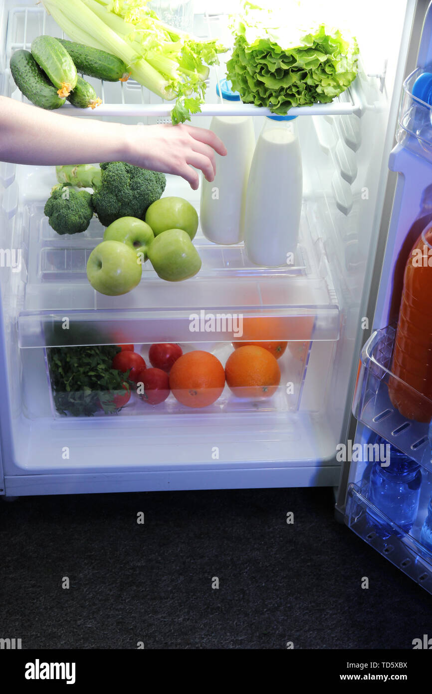 Woman's hand reaching out for food from the refrigerator, close up ...