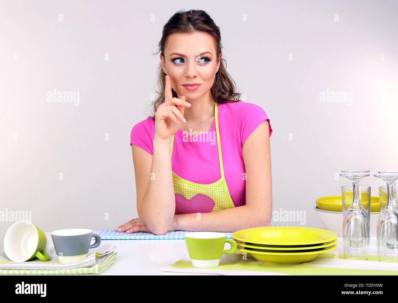 Beautiful young woman wipes clean utensils in kitchen on grey ...