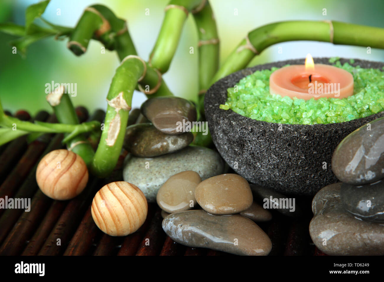 Still life with green bamboo plant and stones, on bamboo mat, on bright ...