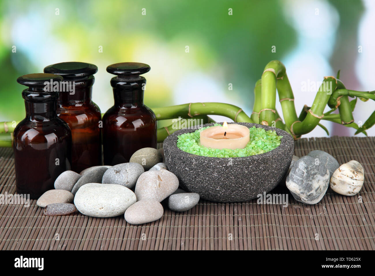 Still life with green bamboo plant and stones, on bamboo mat, on bright ...
