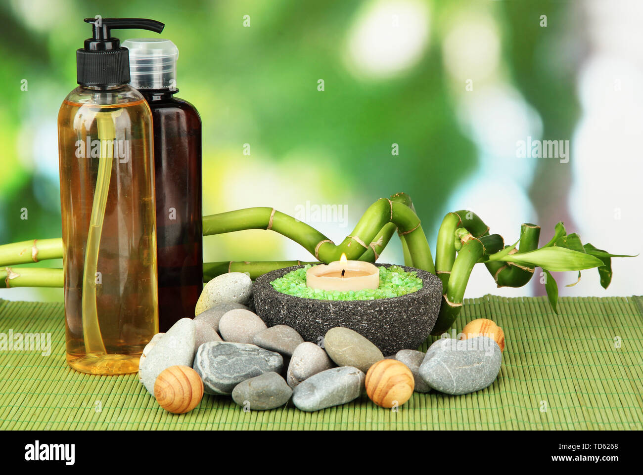 Still life with green bamboo plant and stones, on bamboo mat, on bright ...