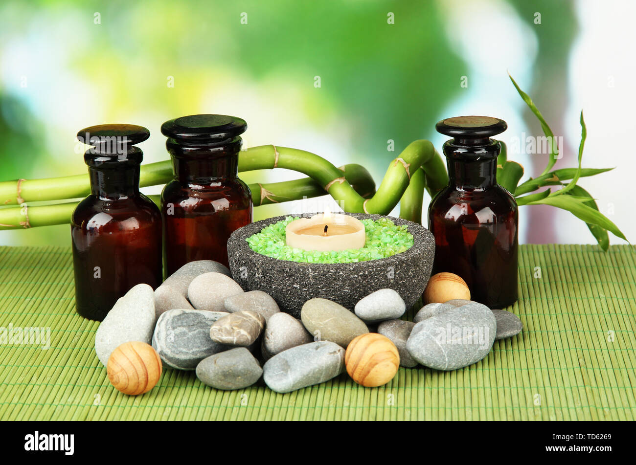 Still life with green bamboo plant and stones, on bamboo mat, on bright ...