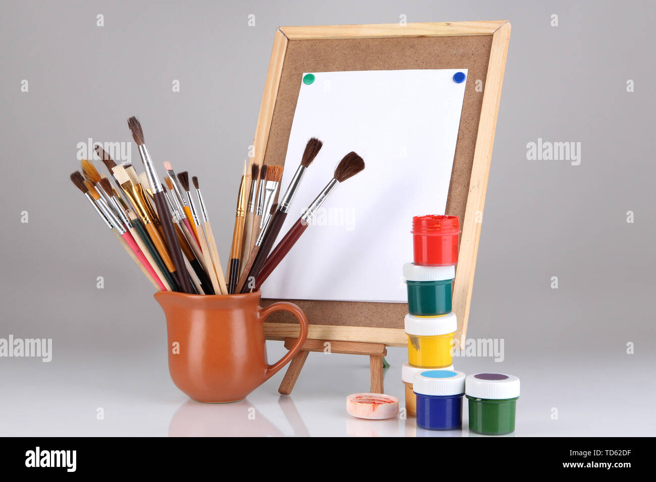 Small easel with sheet of paper and art supplies isolated on white ...